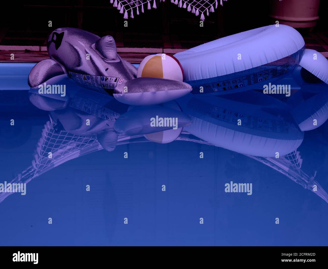 ball and plastic floats pushed by the wind to the edge of a pool with ...