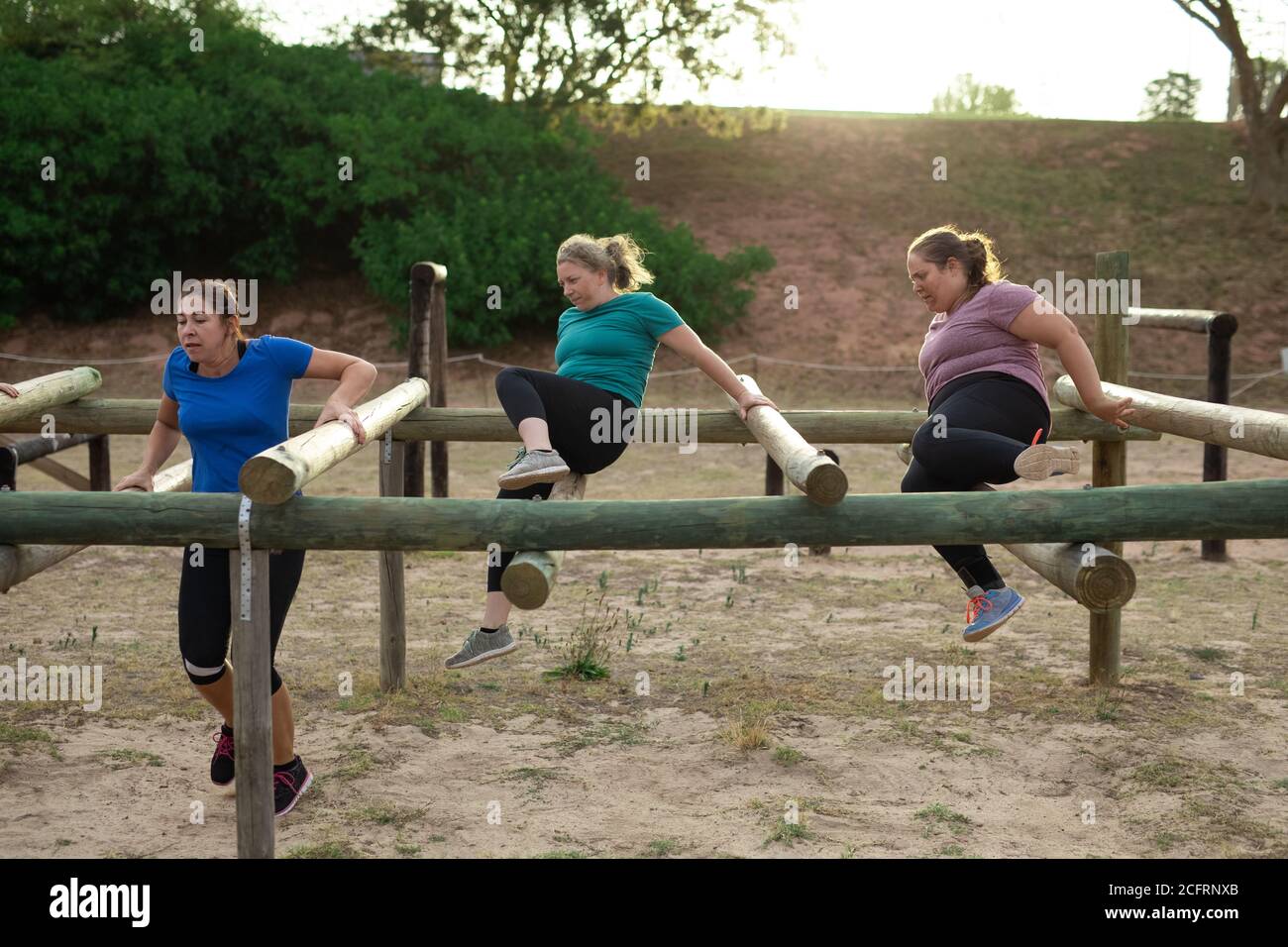 Group of woman climbing through obstacle course at boot camp Stock ...
