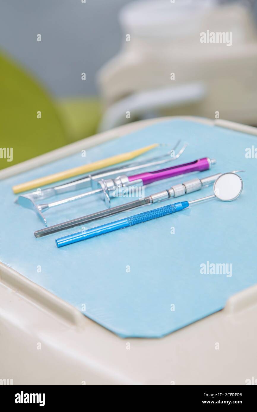 closeup of a dentist's tools of diferent colors and size on a blue ...