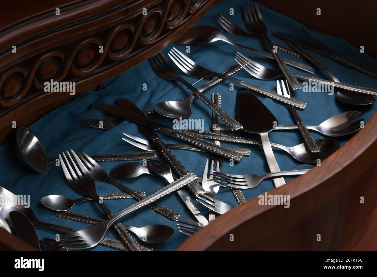 Carved wooden crate with scattered silver cutlery with turquoise ...