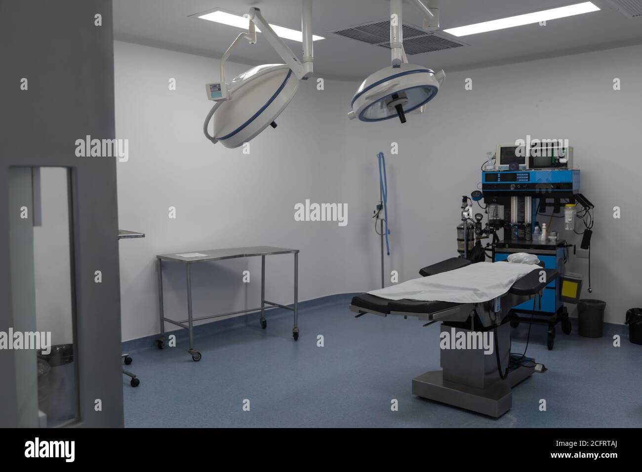 white medical center room, with a stretcher, lamps, tables and medical ...