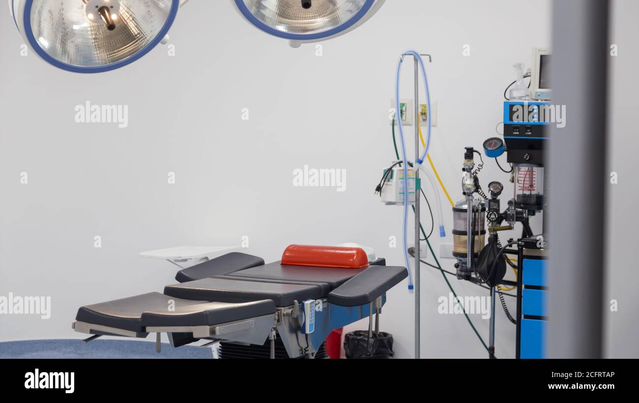 hospital room with a black gurney, medical instruments and lamps, white ...