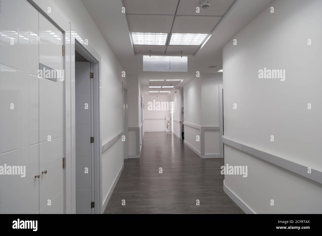 long white corridor, with several doors and partitions, brown floor ...