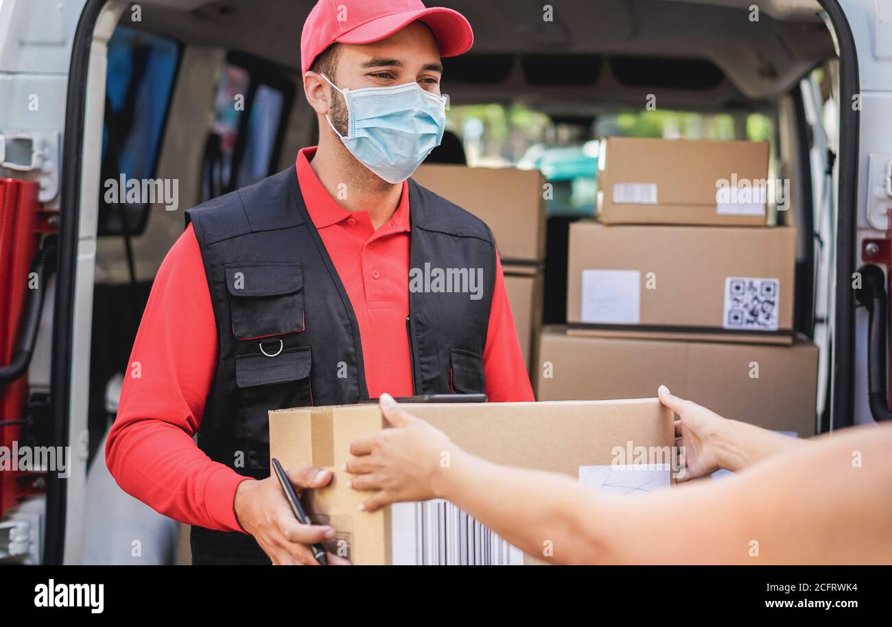Courier delivering packages with truck while wearing protective face ...
