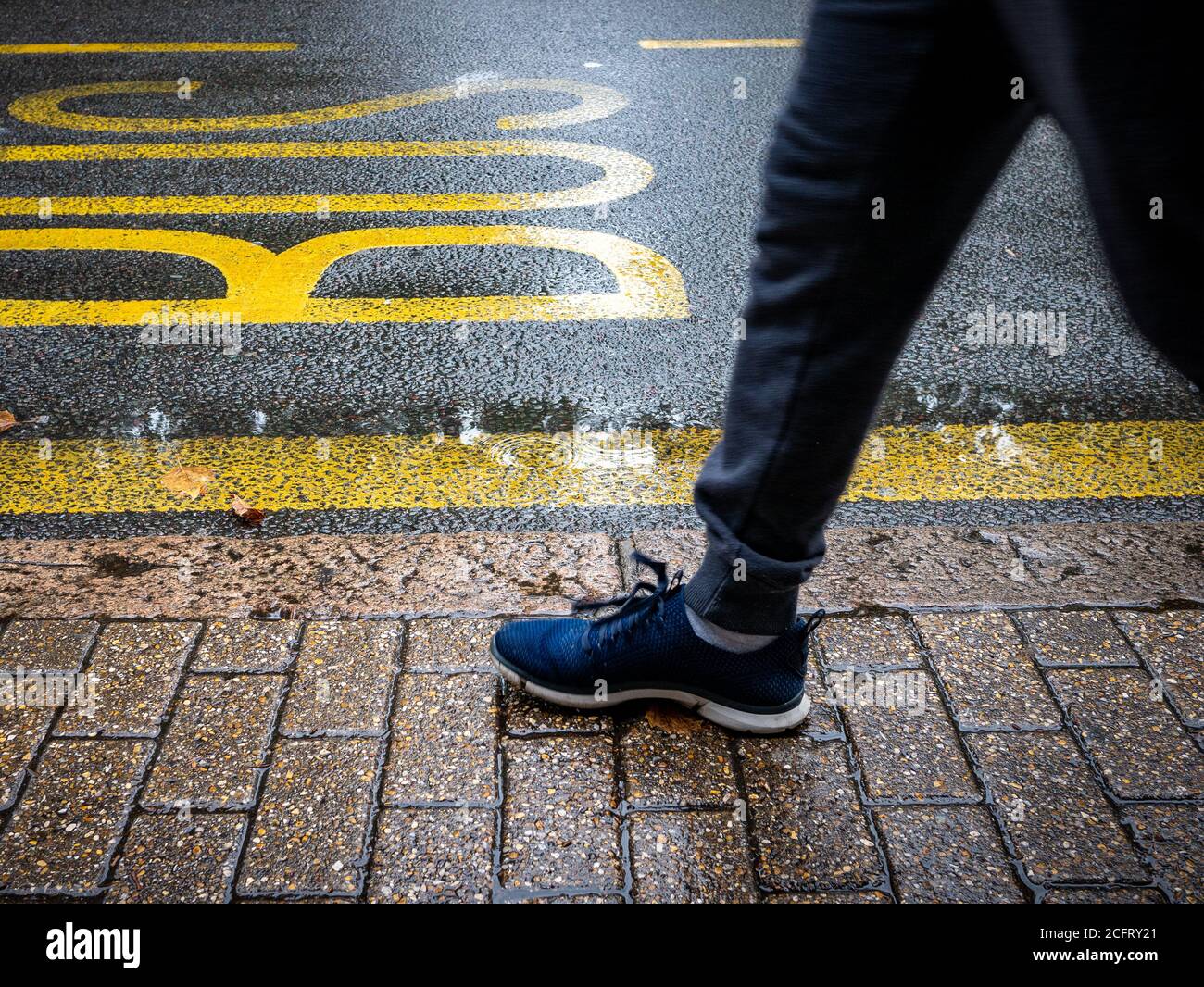 Persons legs and feet walking by the pavement on a wet rainy day in ...