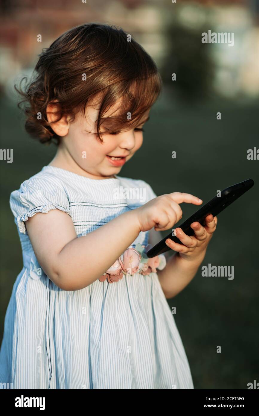 Cute, little two year old girl smiles and touches something on the ...