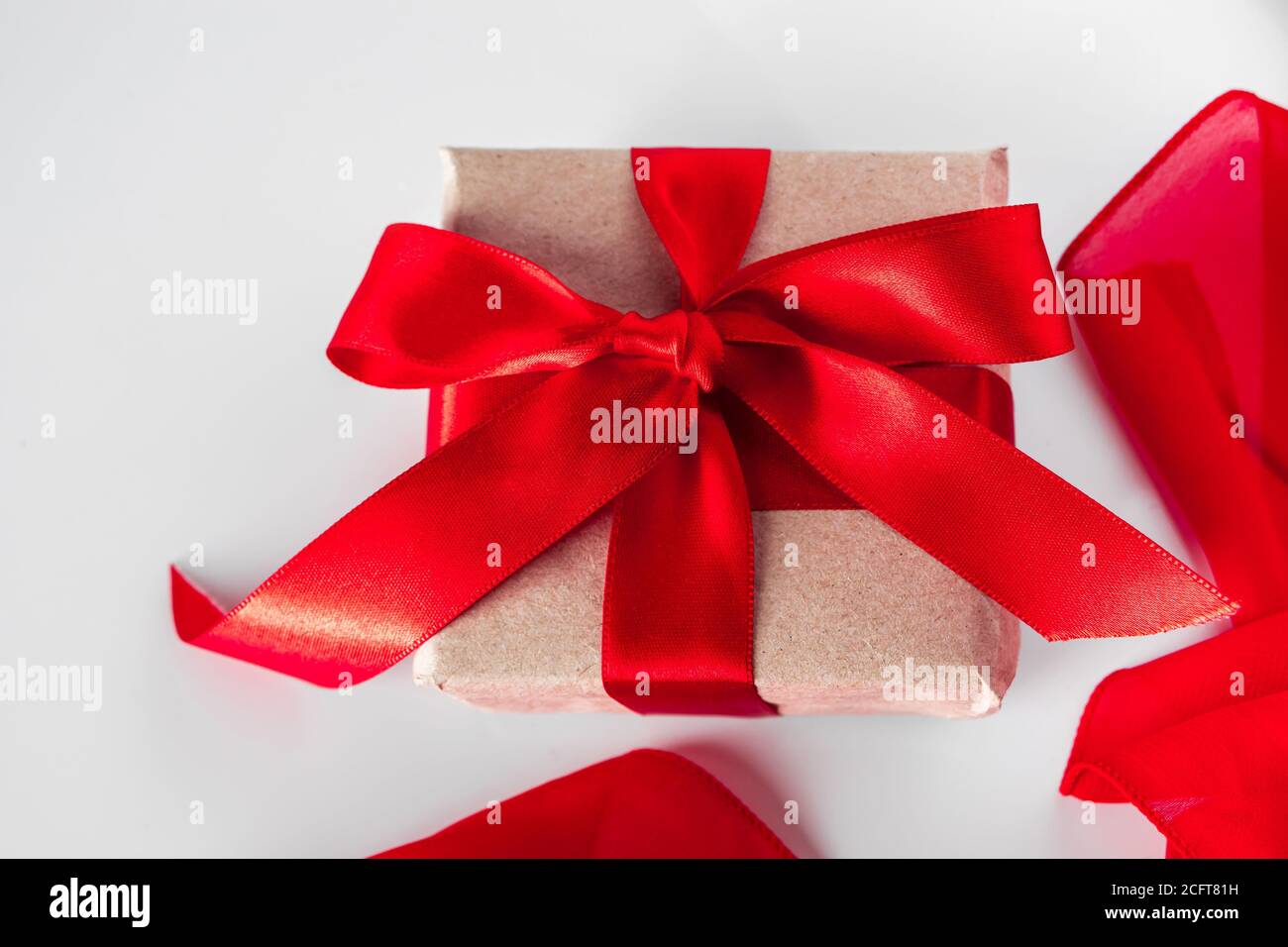 Gift box with craft paper and red ribbon on a white background ...