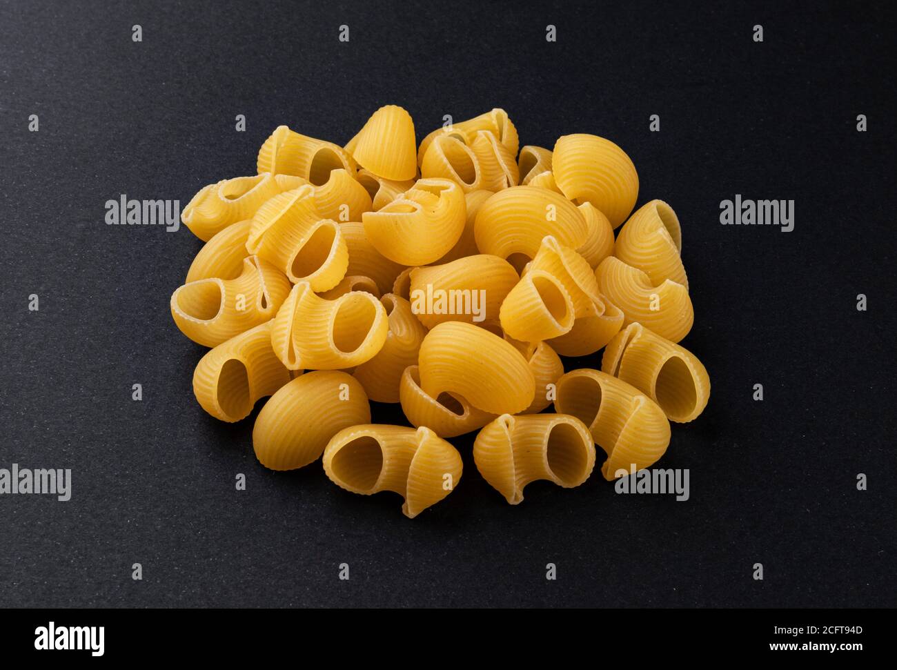 Raw pipe rigate pasta isolated on black background Stock Photo - Alamy