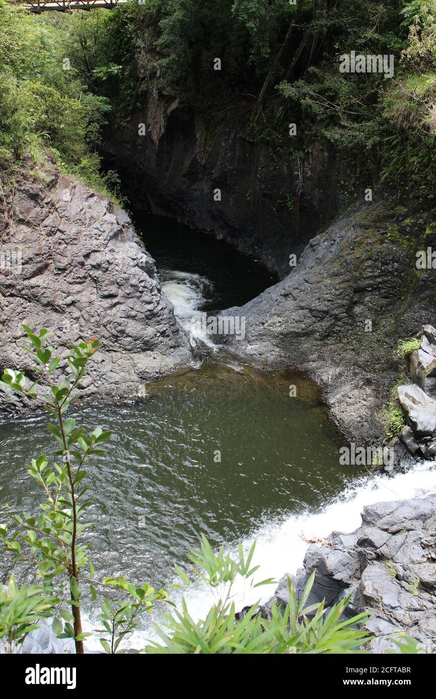 A mountain stream cascading down volcanic rock on the Pipiwai Trail in ...