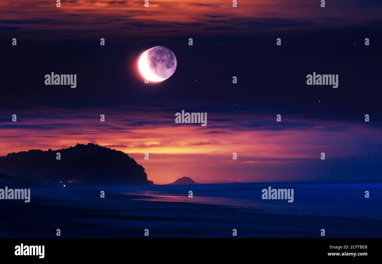 Full moon rising above ocean coast Stock Photo - Alamy