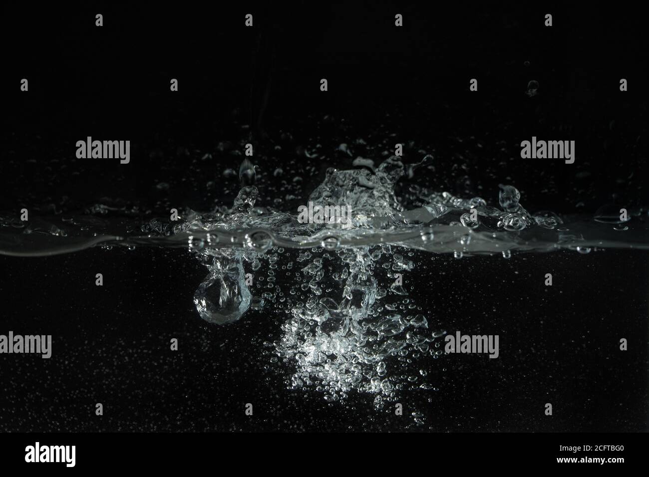 Water splashing as it's poured into aquarium tank, black background ...