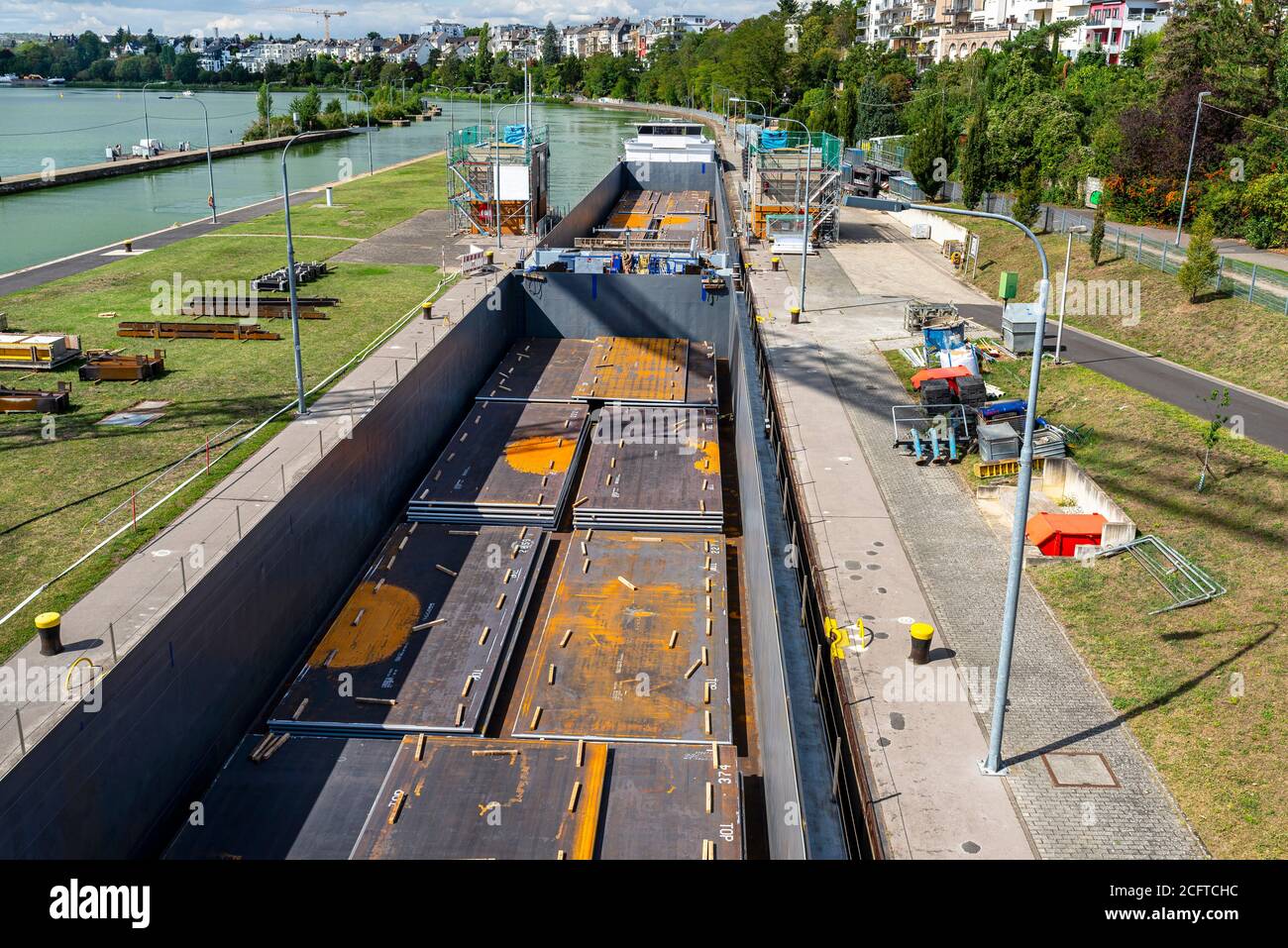 Double barge filled with sheets of thick metal, flowing into the river ...