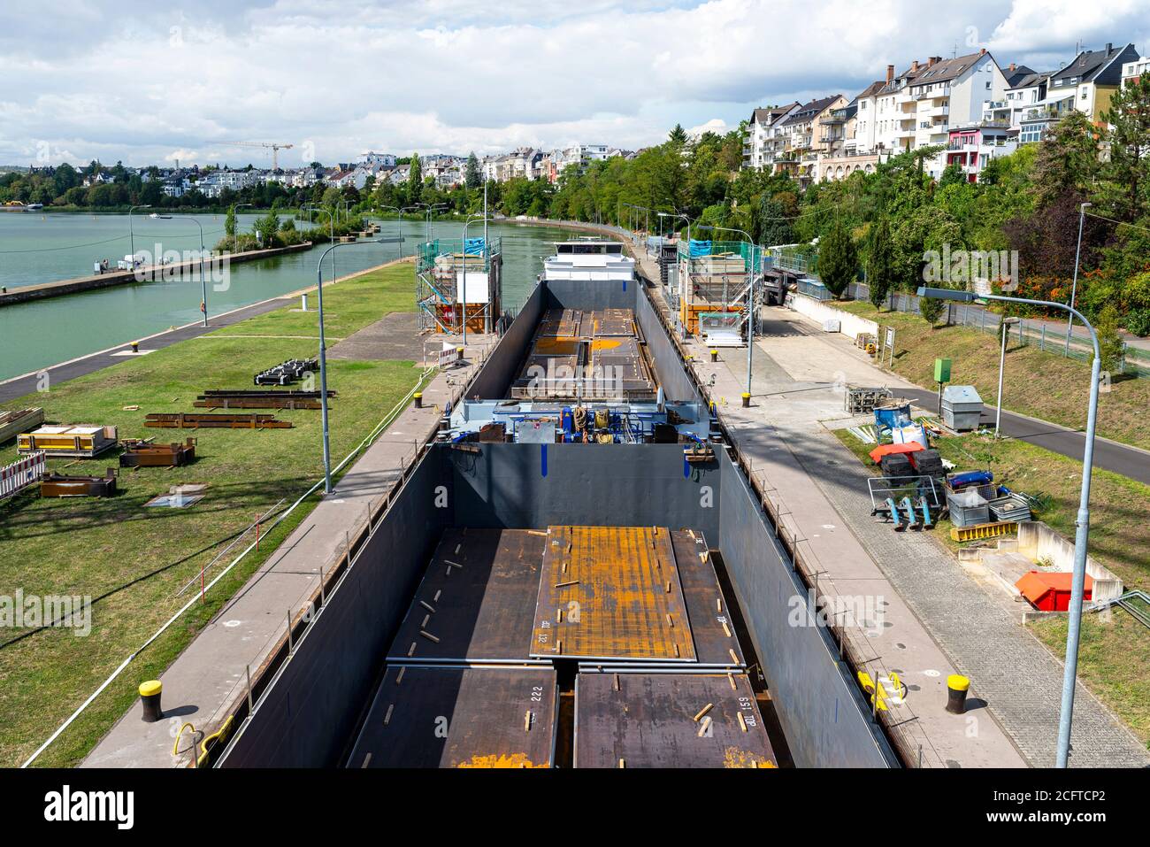Double barge filled with sheets of thick metal, flowing into the river ...