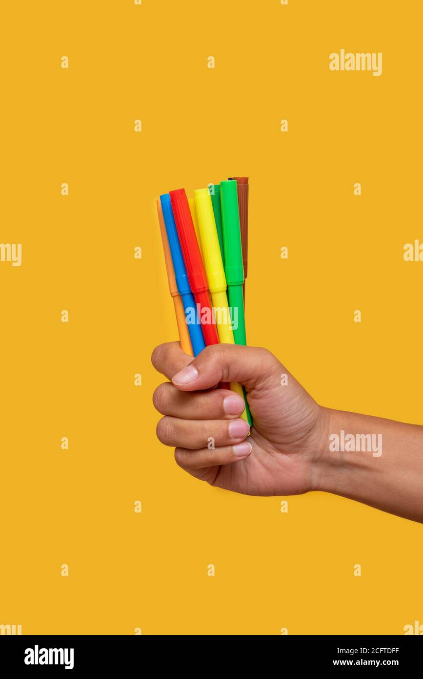 Hand holding colored markers on orange background Stock Photo - Alamy