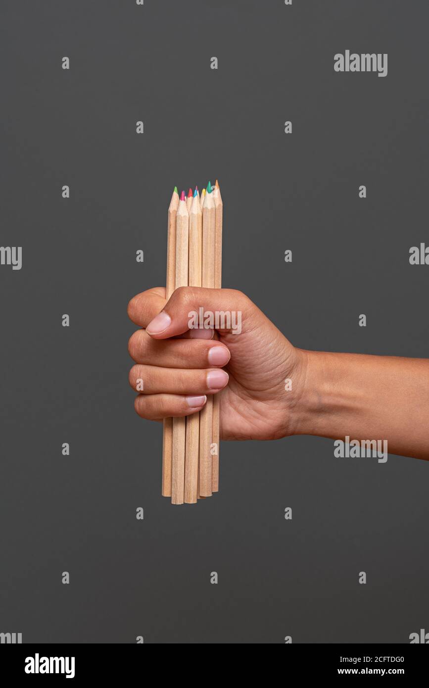 Hand holding colored crayons on grey background Stock Photo - Alamy