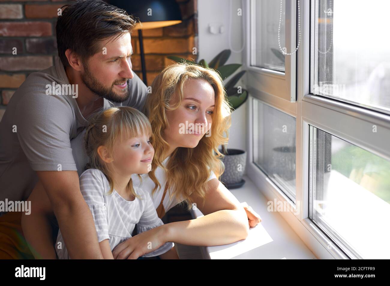 happy young family looking through the window at home, look at the ...