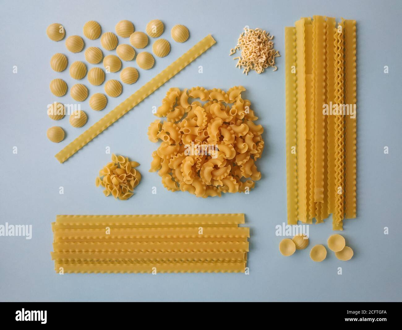 Different types of uncooked pasta, blue background. Food knolling, top ...