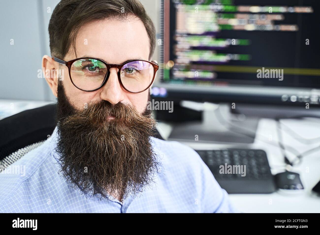Closeup portrait of a serious computer programmer developer working in IT office, sitting at ...