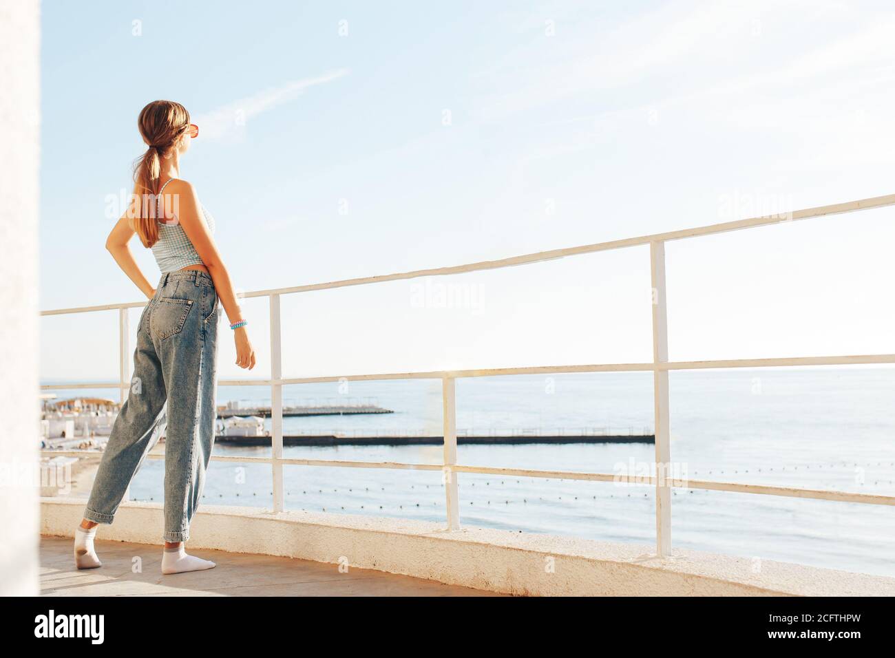 beautiful young woman standing on the balcony morning and looking at ...