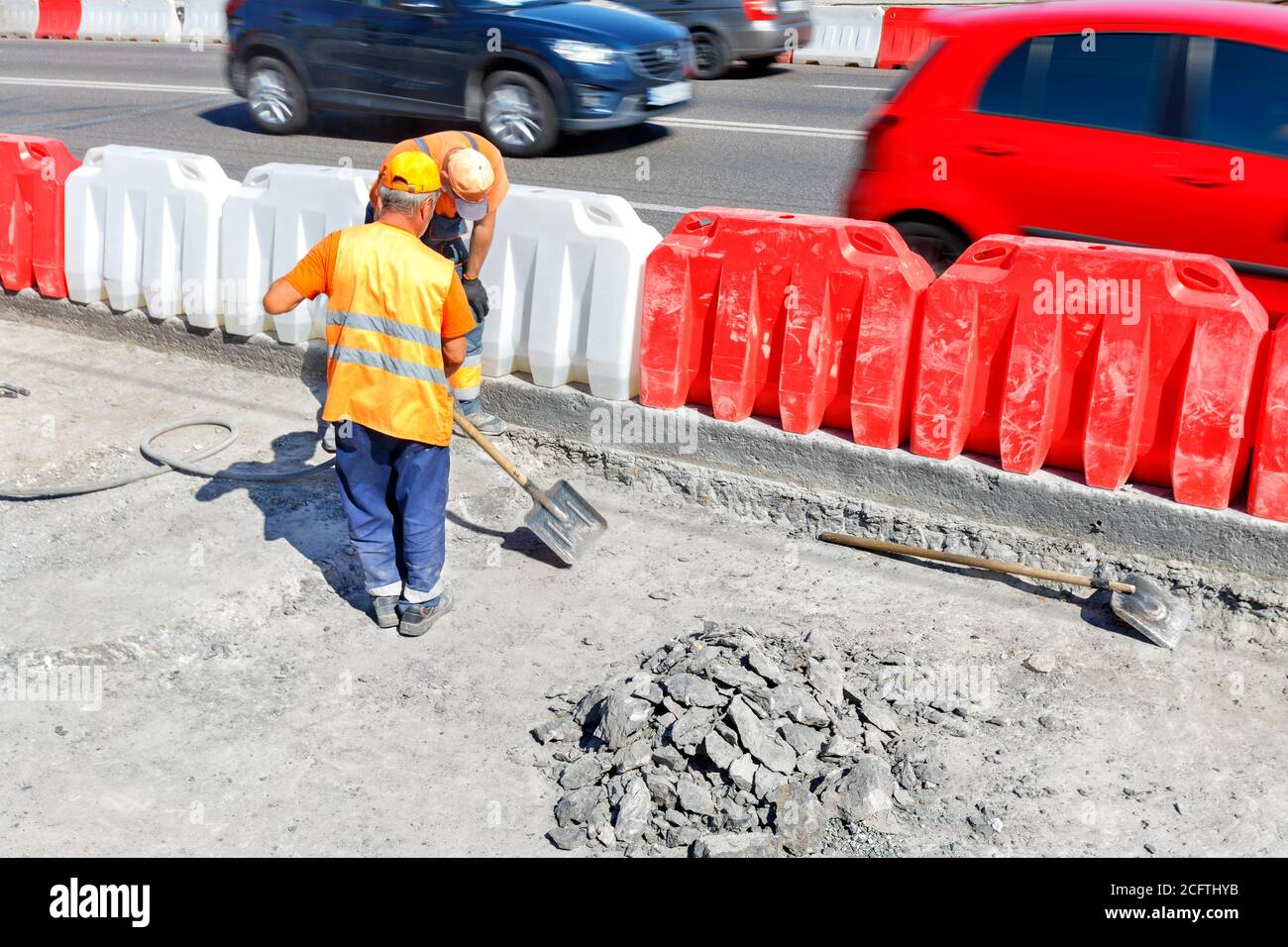 Road workers knock down old concrete during road repairs and shovel a ...