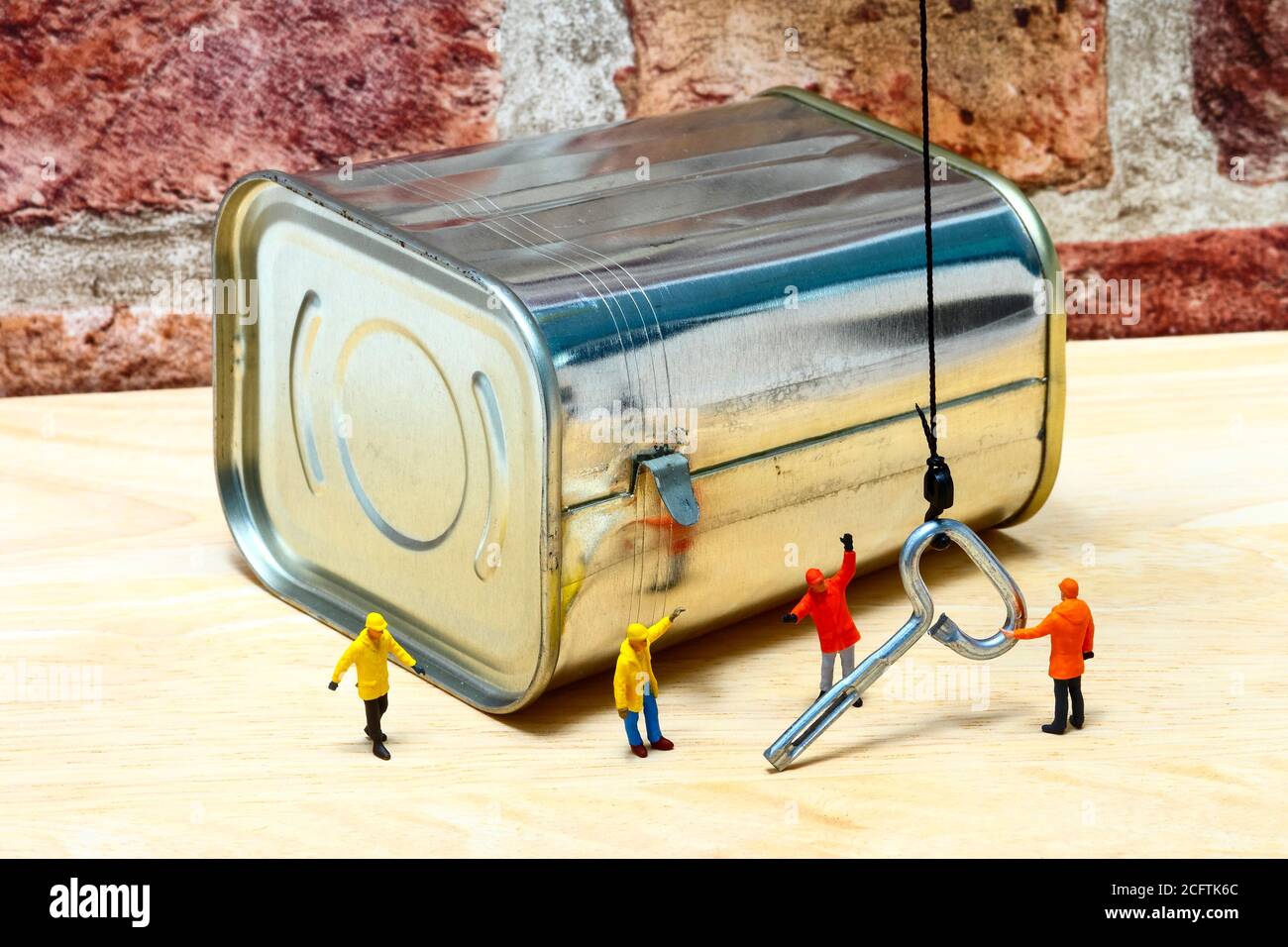 Miniature figure workman using a crane to manoeuver the key for a ...