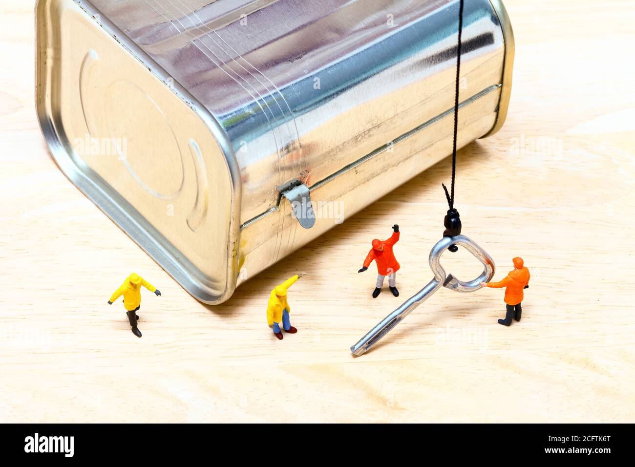 Miniature figure workman using a crane to manoeuver the key for a ...