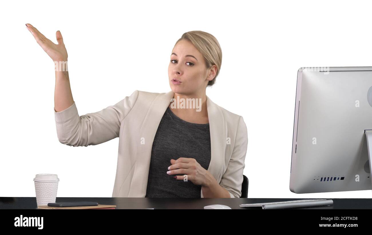 Lady looking and talking to camera at her work desk and pointing to the ...