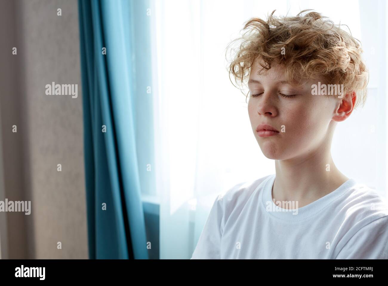 calm redhead curly boy dream with eyes closed, young boy sits thinking ...