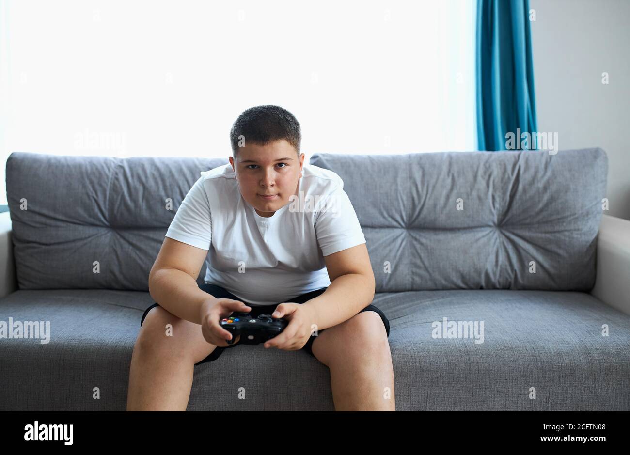 fat caucasian teenager boy enjoys video games, overweight boy sits on ...