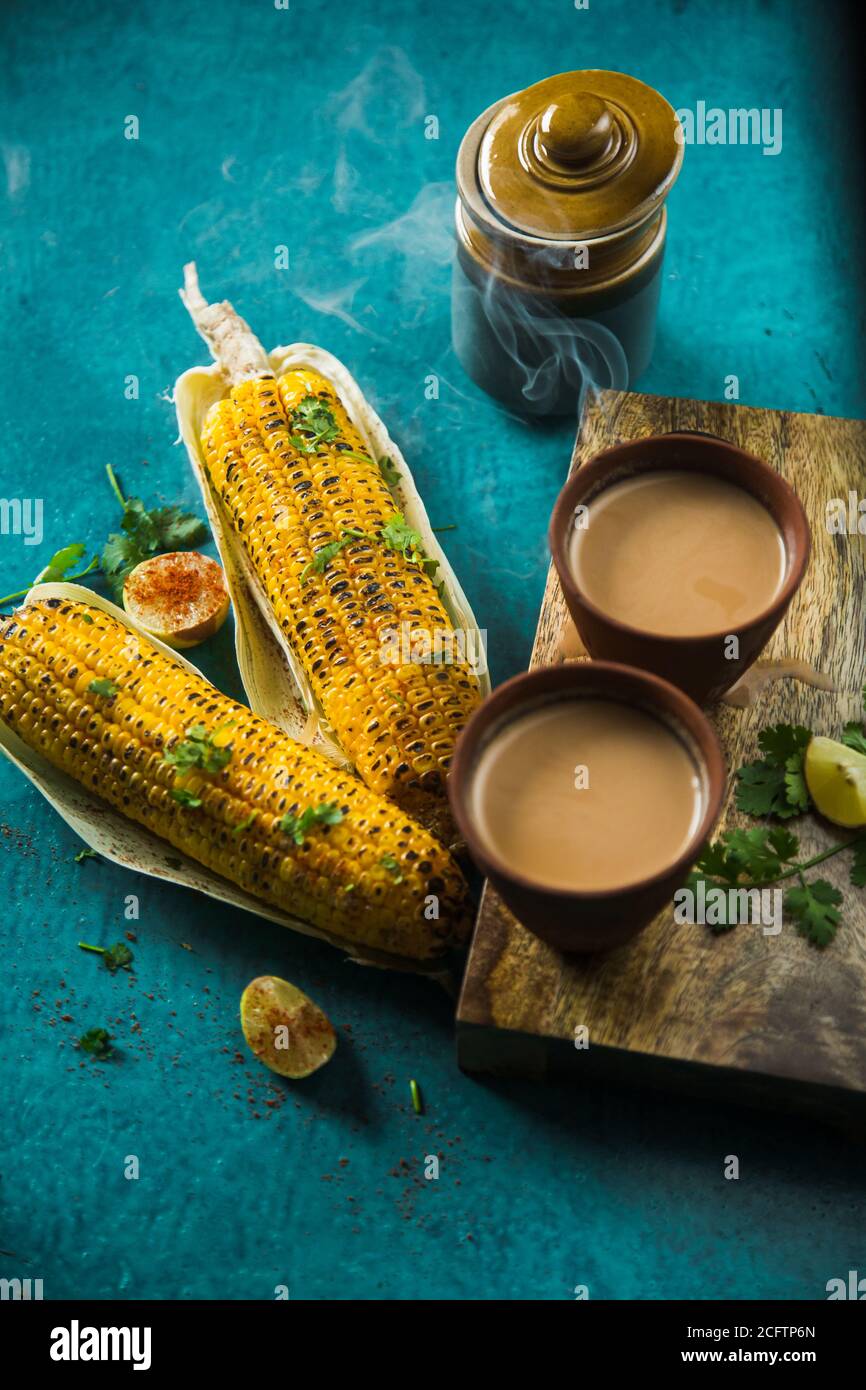 Top view of brewed hot milk tea with roasted grilled corn on blue ...
