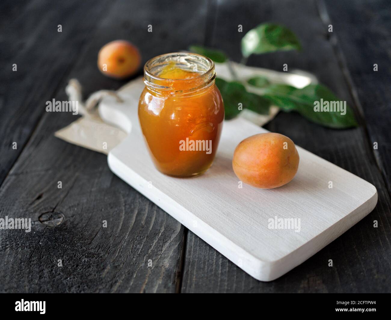 Fresh apricots and apricot jam in jar on rustic wooden table. Close up ...