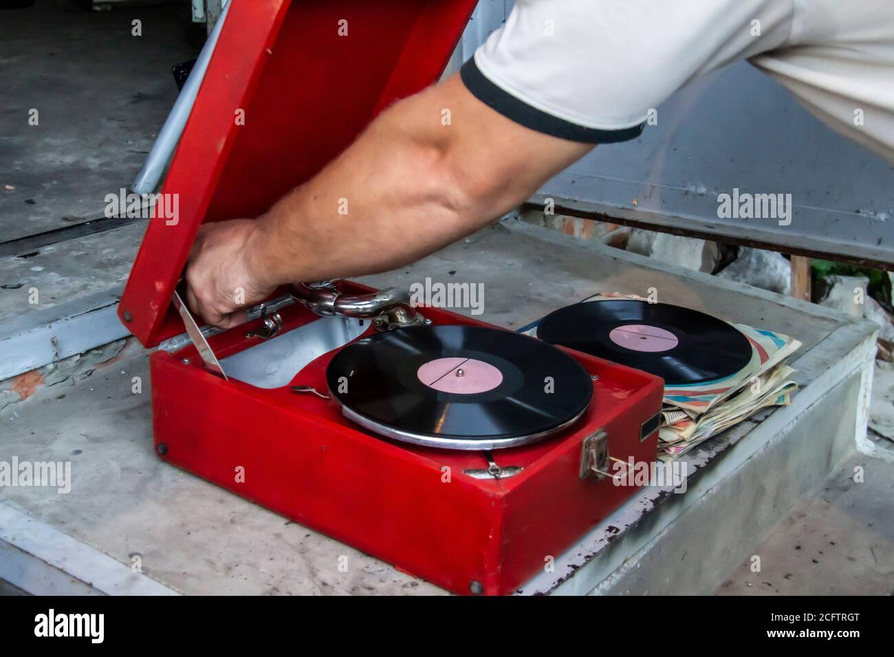 Old red vintage record player with vinyl record outside house. A hand ...