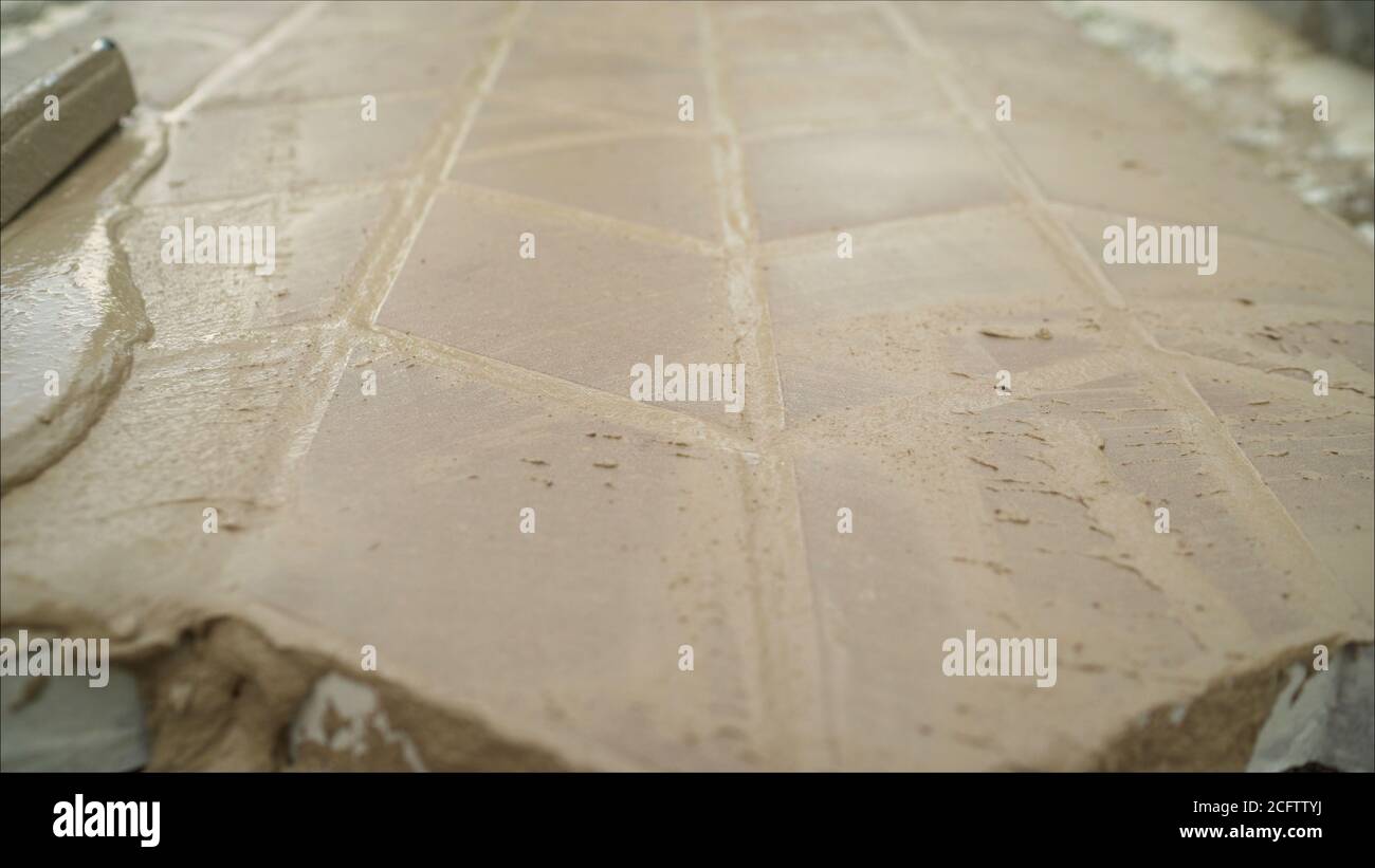 Paving slabs with mortar. Worker levels concrete with a spatula, hands ...