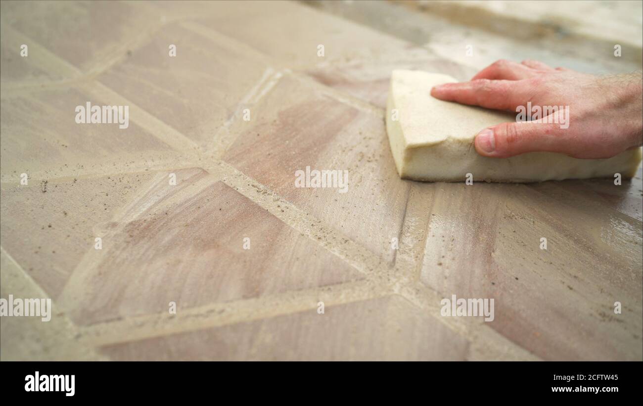 poorly laid pavement tiles on a walkway in the park. Worker makes ...
