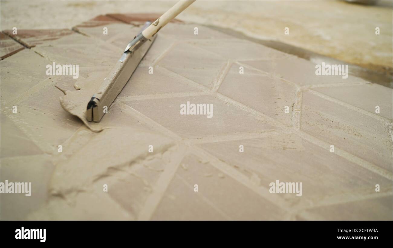 poorly laid pavement tiles on a walkway in the park. Worker makes ...