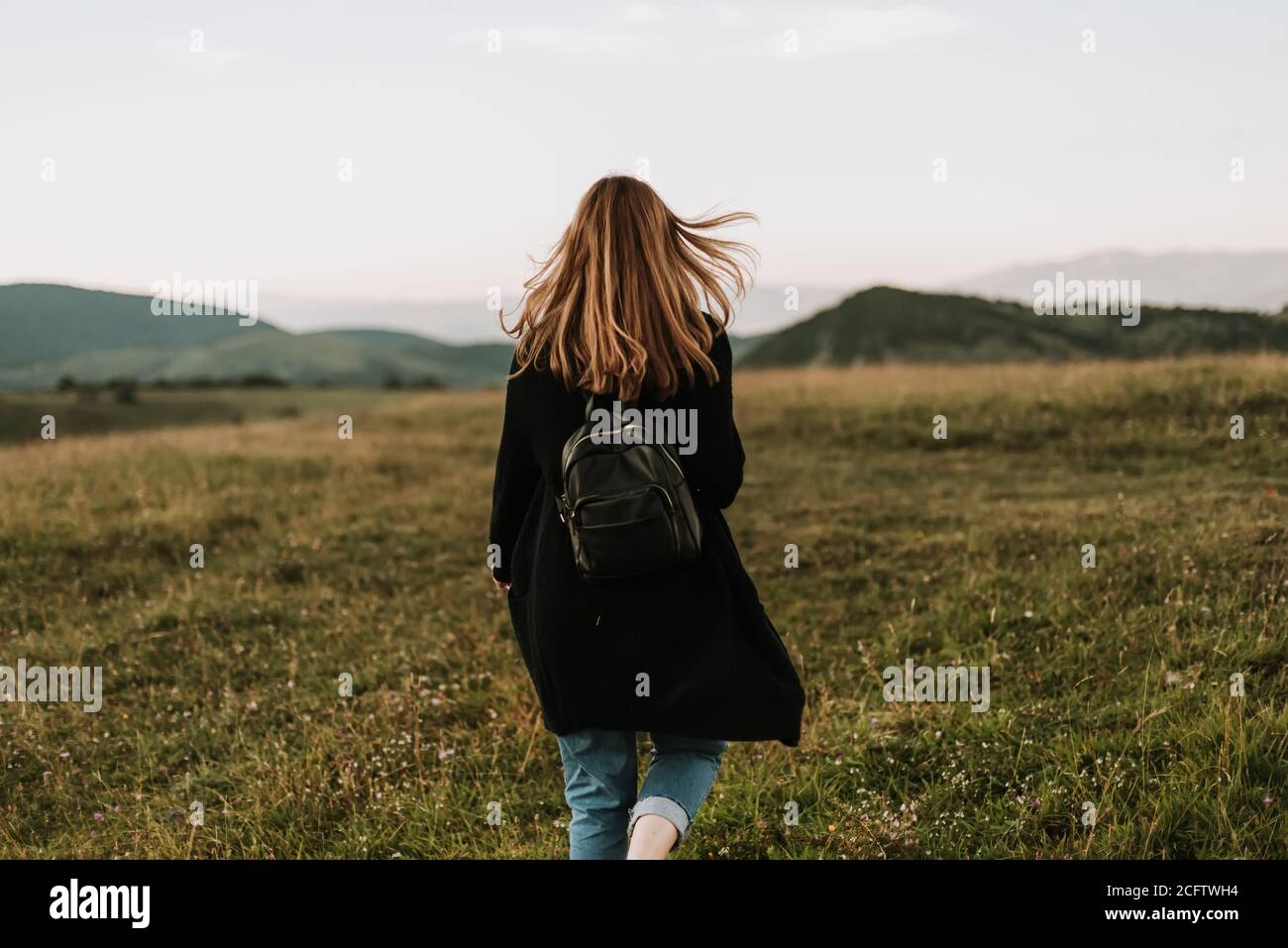 Girl with backpack walking in nature Stock Photo - Alamy