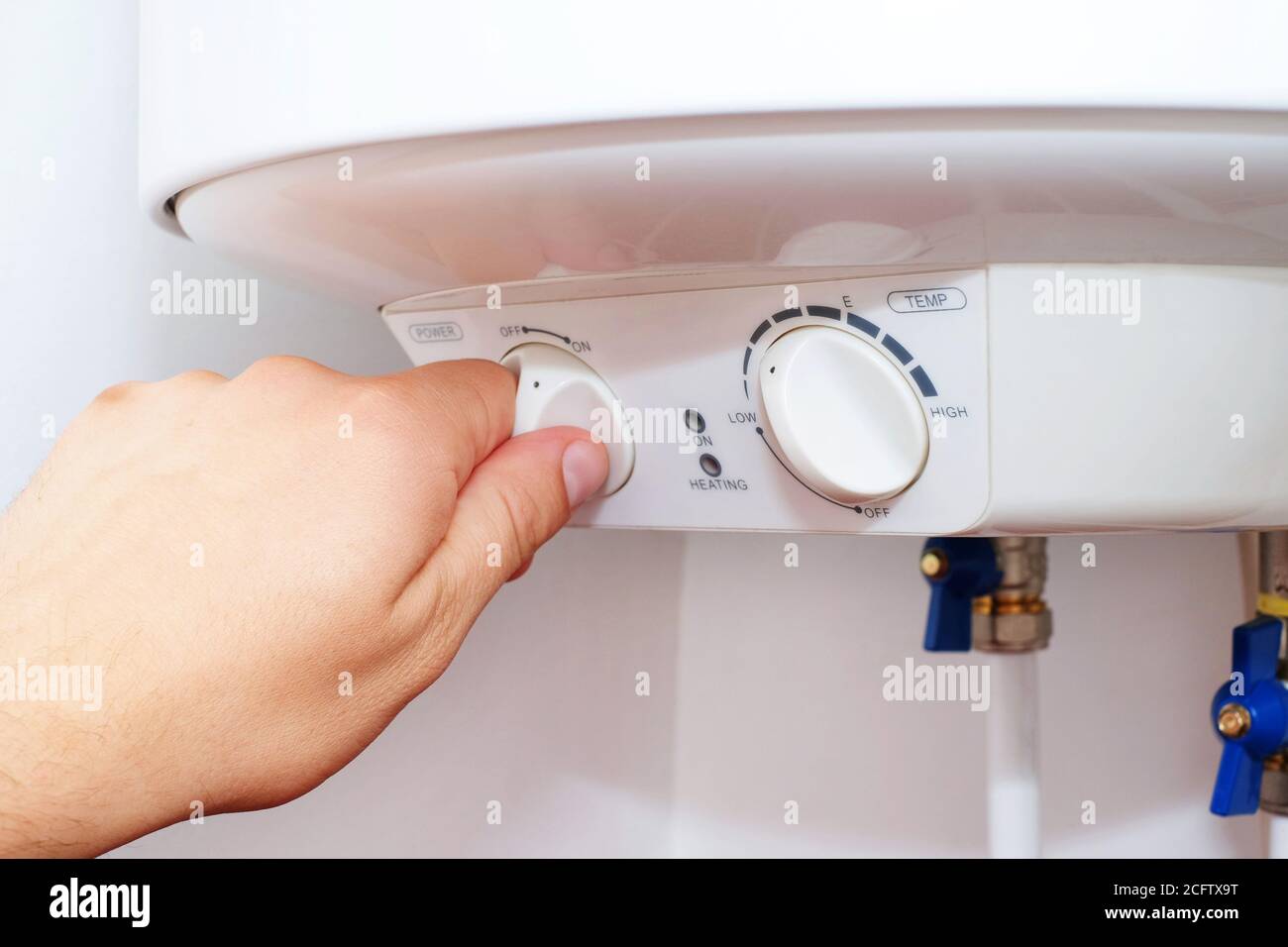 Man turns on the switch on control panel of home electric water heater ...