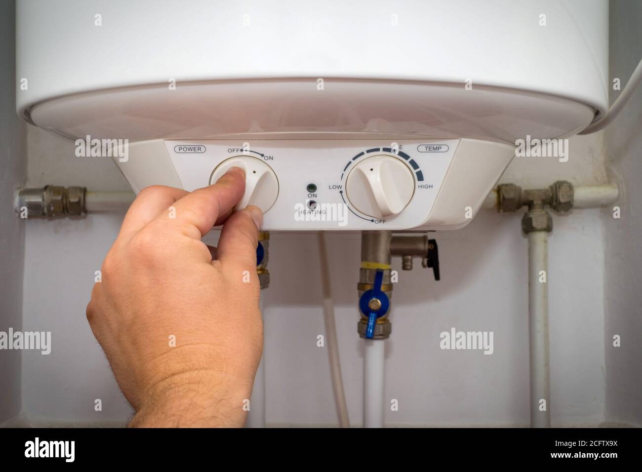 Man turns on the switch on control panel of home electric water heater ...