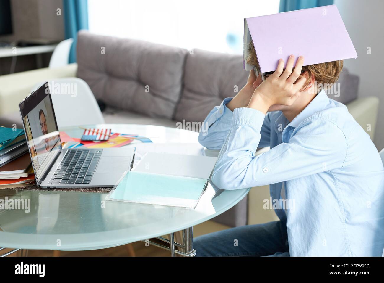 sad schoolboy tired of studying online at home, look at screen of ...