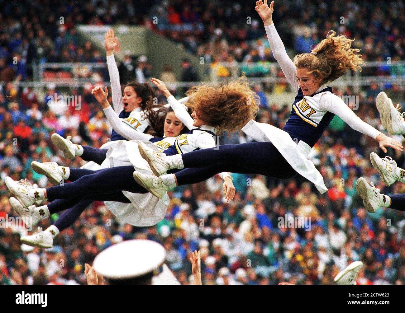 U.S. Naval Academy cheerleaders are tossed high in the air during the ...