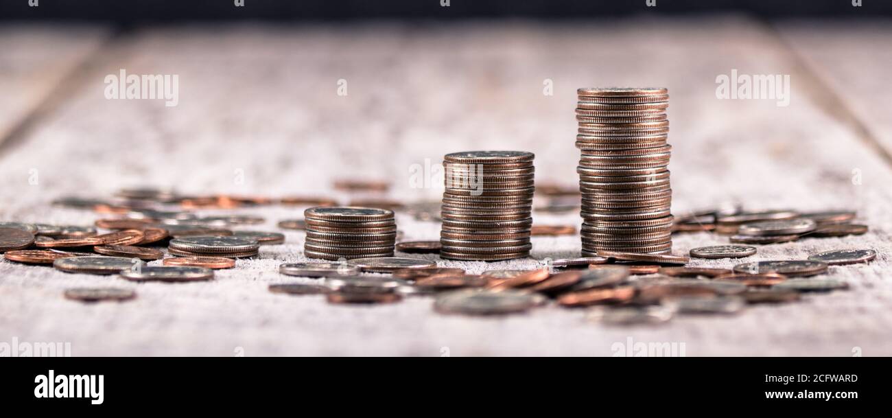 Stacks of quarters on an old wooden table amid scattered coins ...