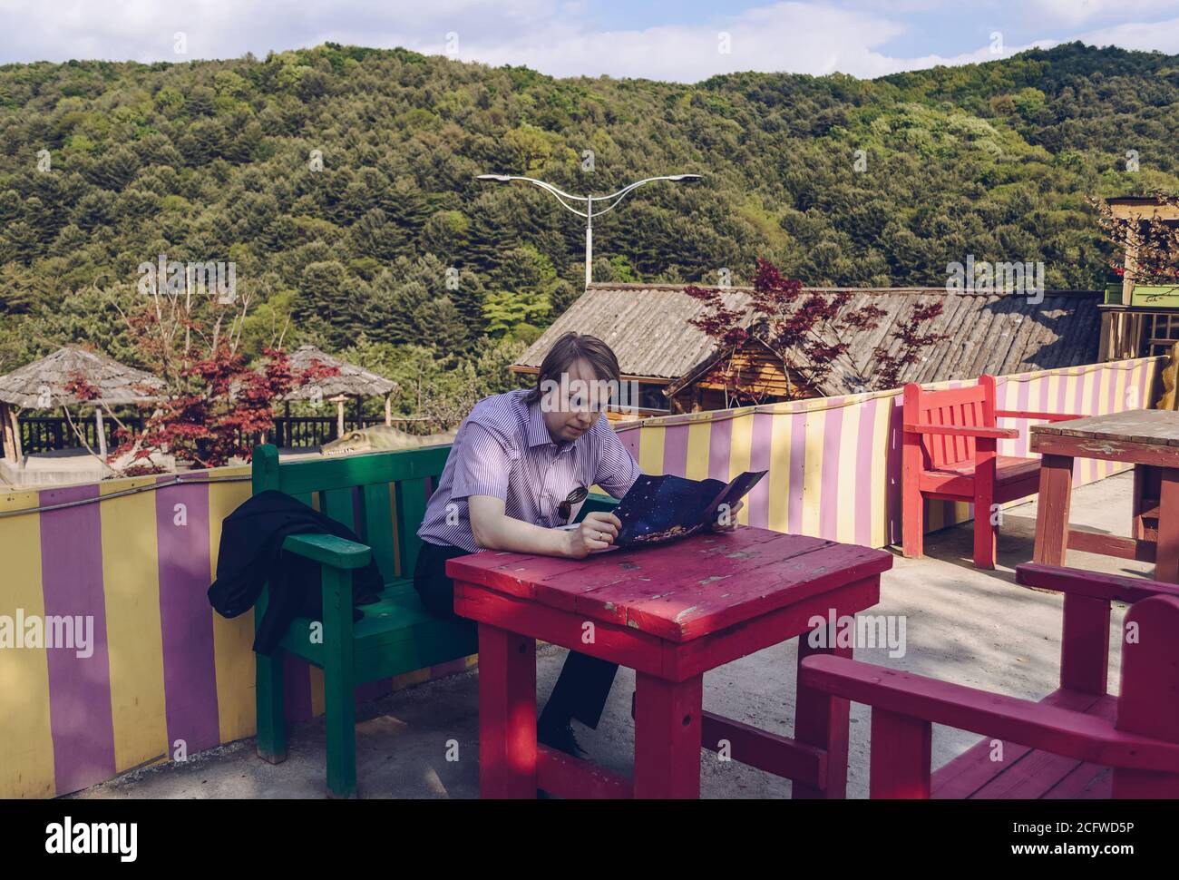 man is sitting and reading brochure with korean mountains on background ...
