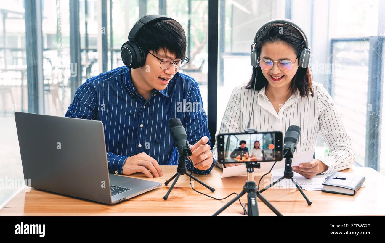 Asian Man and woman podcasters in headphones recording content with ...