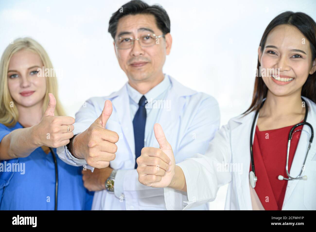 Group of doctors wearing formal white coat and blue scrubs suit, Thumbs ...