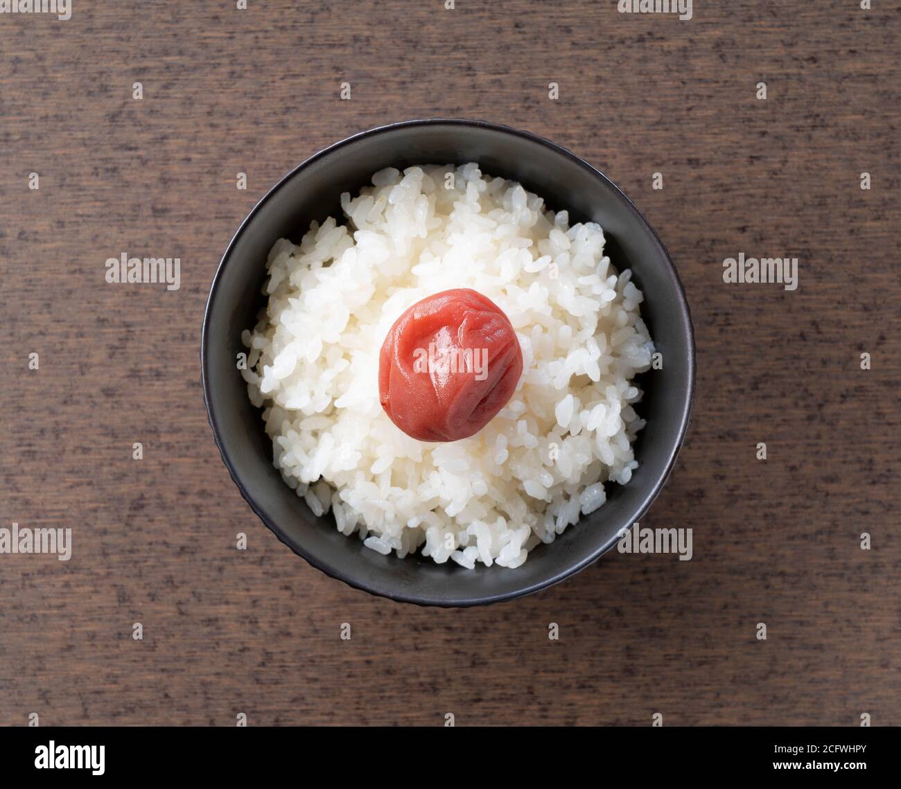 A bird's-eye view of Japanese pickled plums and freshly cooked rice set ...