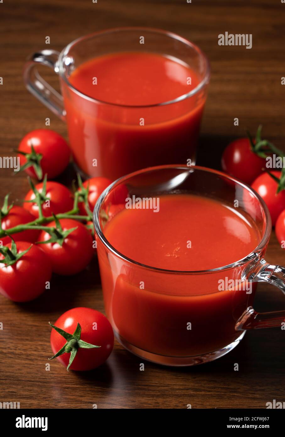 Tomato juice and fresh tomatoes placed against a tree background ...