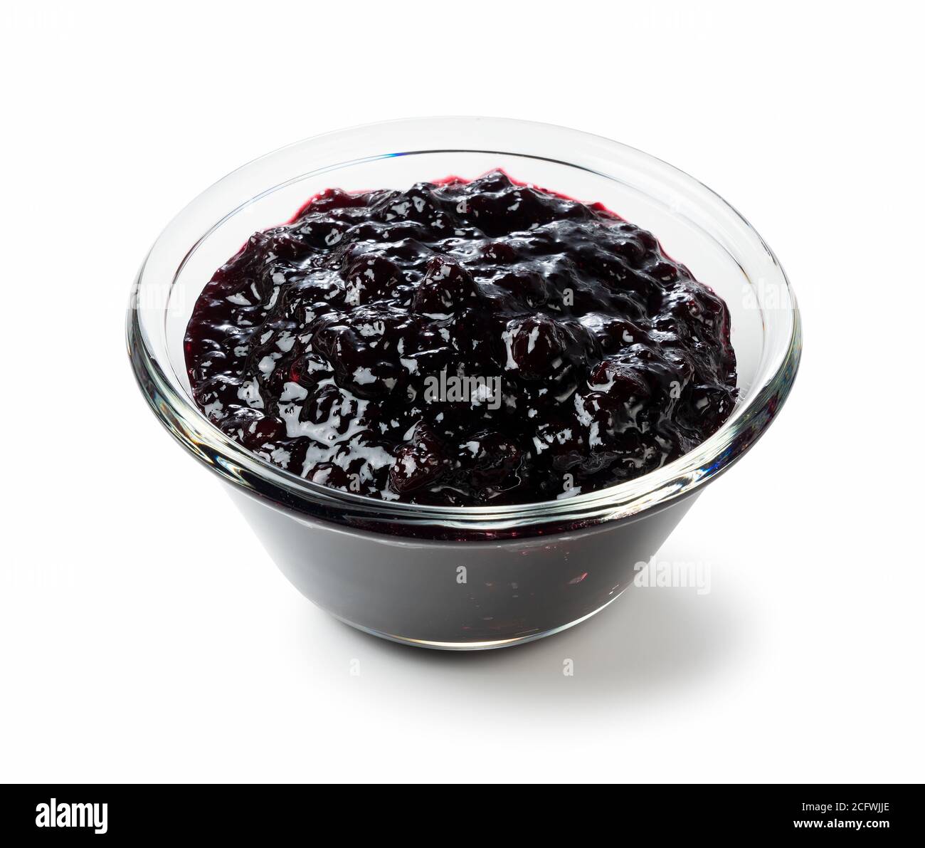Blueberry jam in a glass bowl set against a white background ...