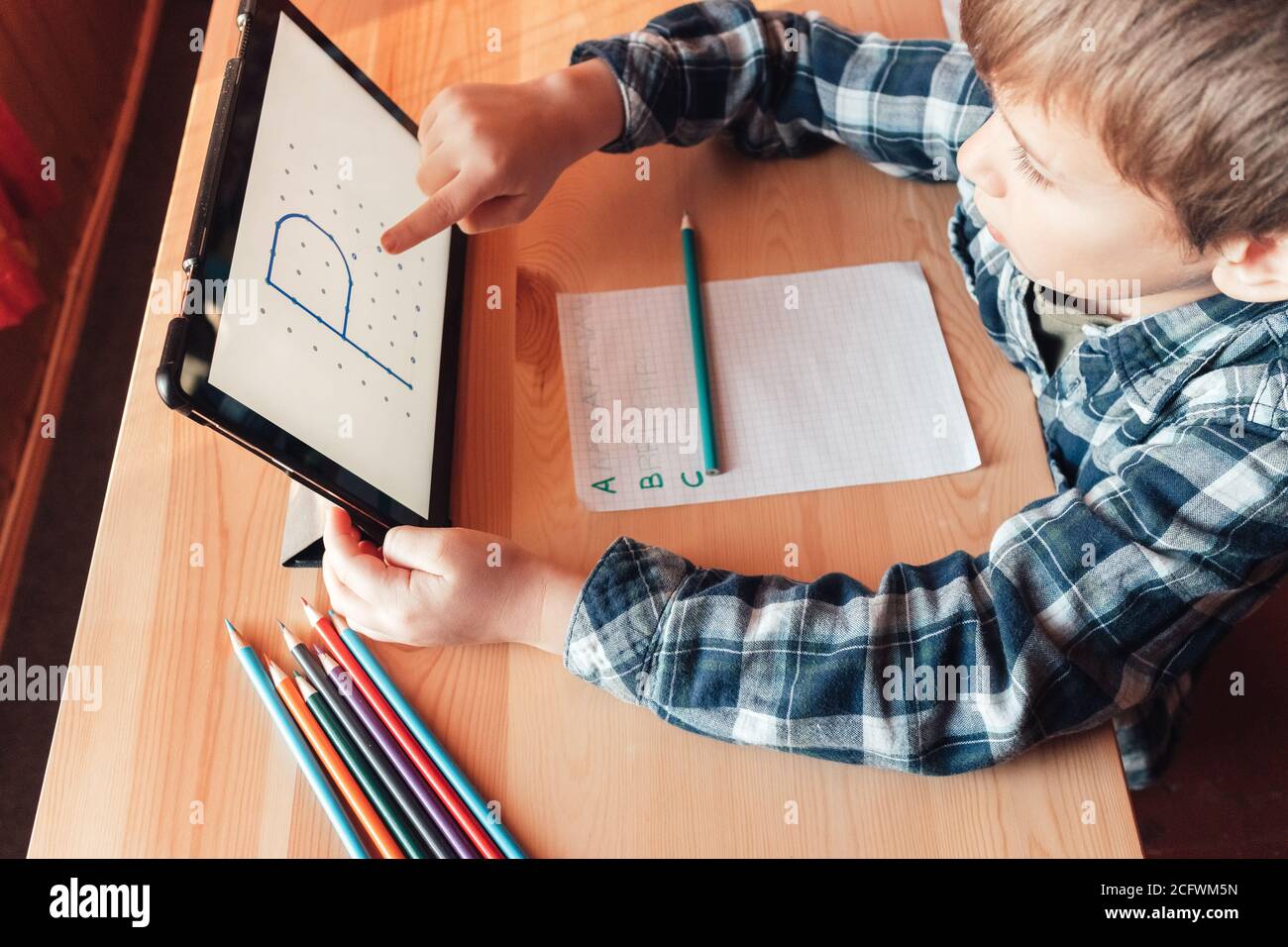 Modern child uses app on tablet to study and draw at home, distance ...