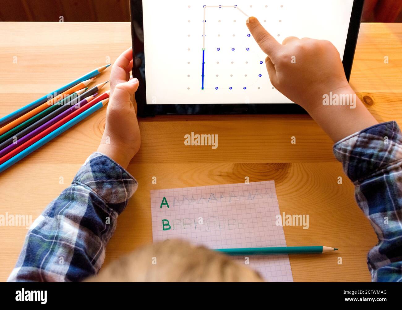 Modern child uses app on tablet to study and draw at home, distance ...