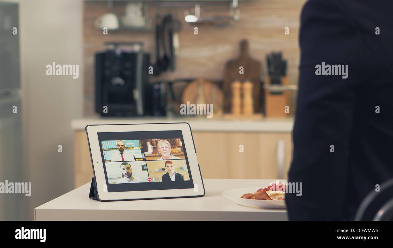 Business woman using smart device while eating breakfast in kitchen ...